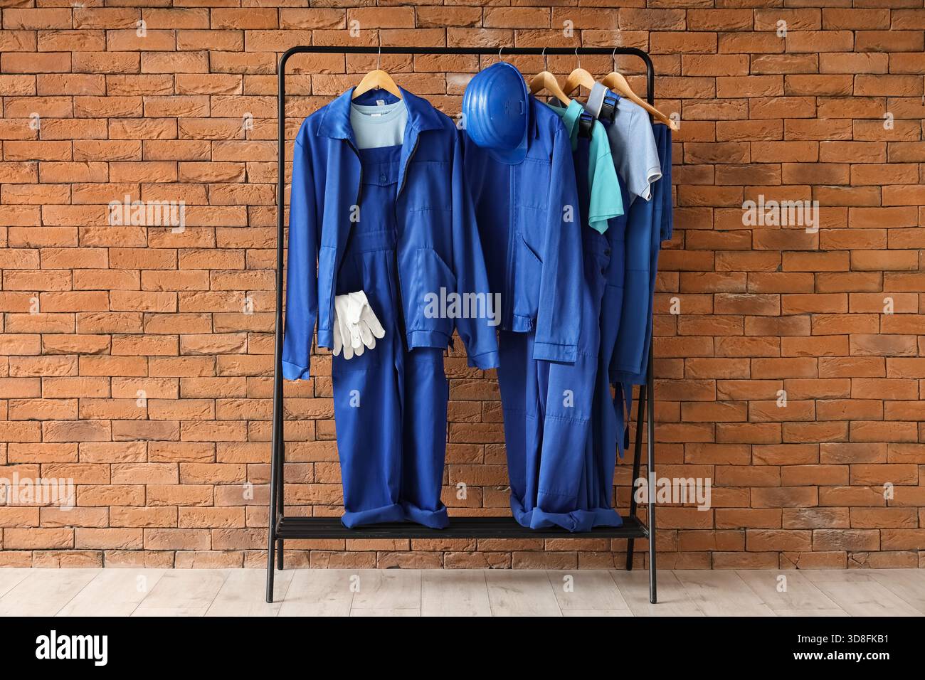 Rack with worker's uniform near brick wall Stock Photo - Alamy