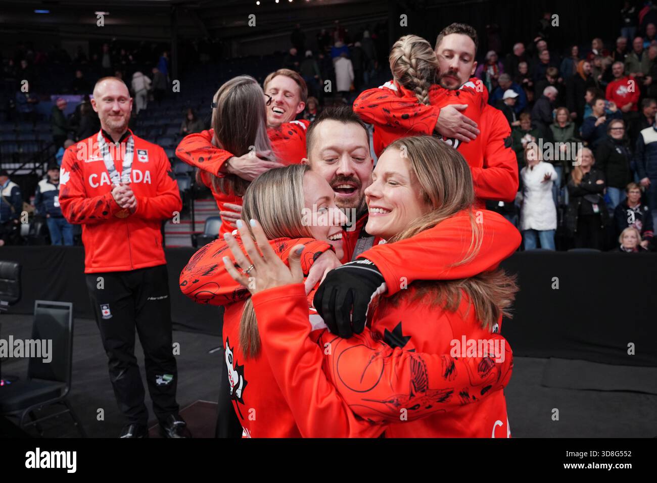 Ben Hebert hugs Rachel Homan, left, and Sarah Wilkes after the three ...