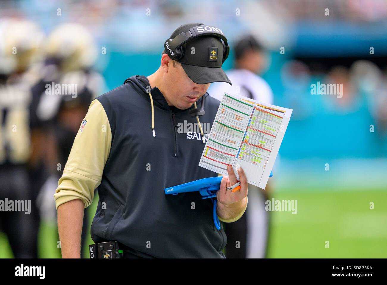 New Orleans Saints head coach Kellen Moore looks down at his tablet on ...