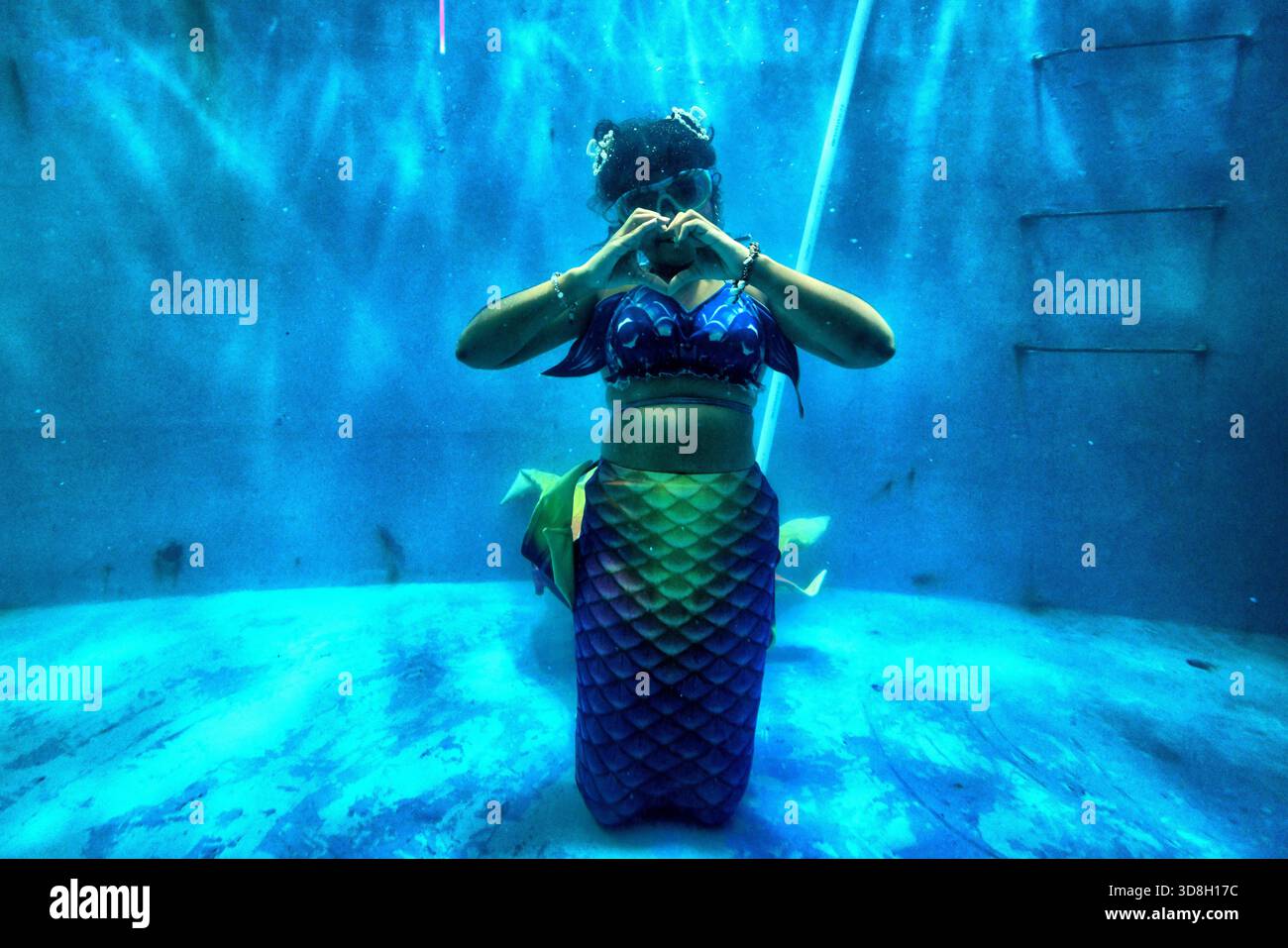 A performer dressed as a mermaid poses for a photo during a mermaid ...
