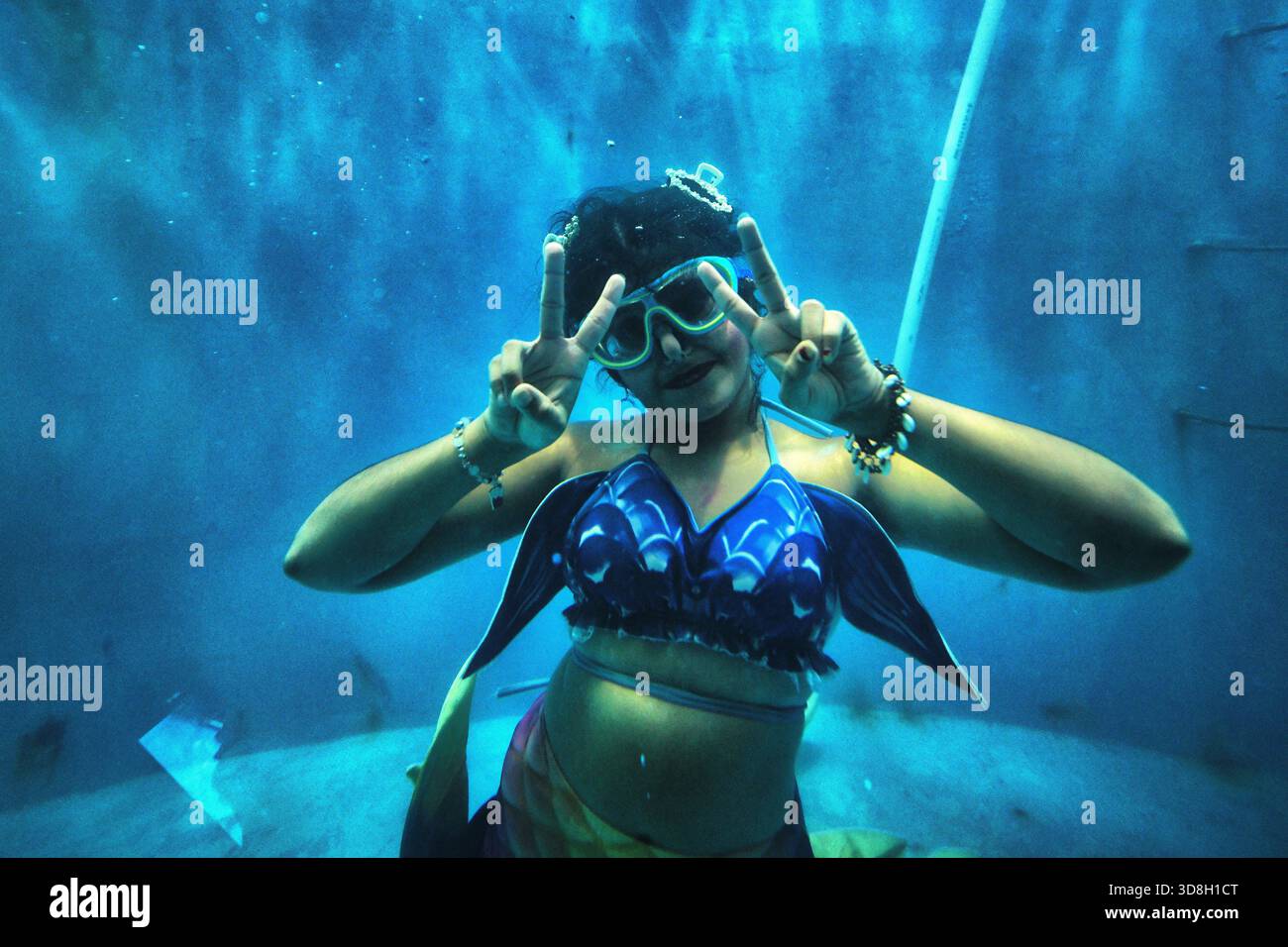 A performer dressed as a mermaid poses for a photo during a mermaid ...