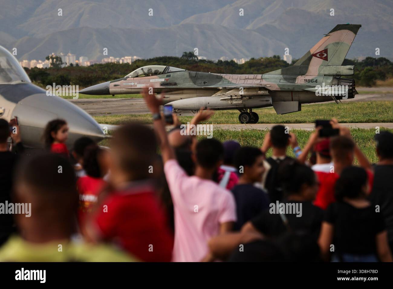 30 November 2025, Venezuela, Maracay: Visitors watch military aircraft ...