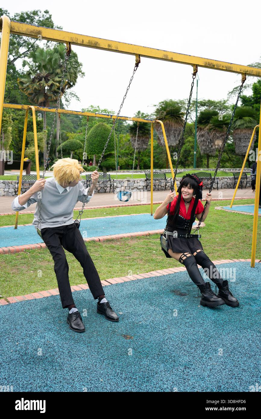 Two cosplayers are enjoying their time swinging on a playground swing ...