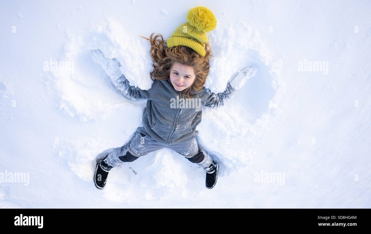 Child lying in snow making angel wings shape. Angel kid play in winter ...