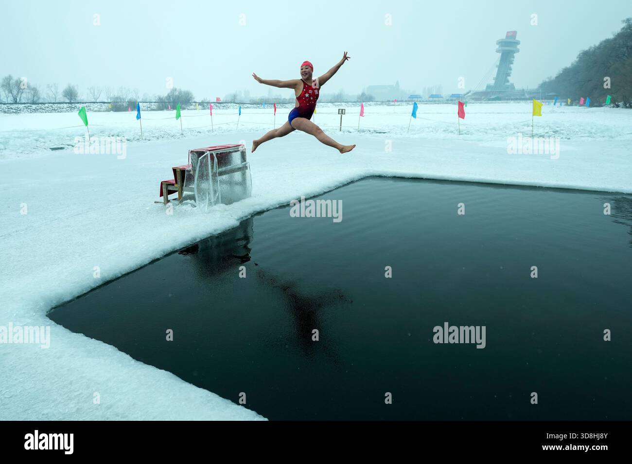 Yu Xiaofeng leaps into a pool carved from ice on the frozen Songhua ...