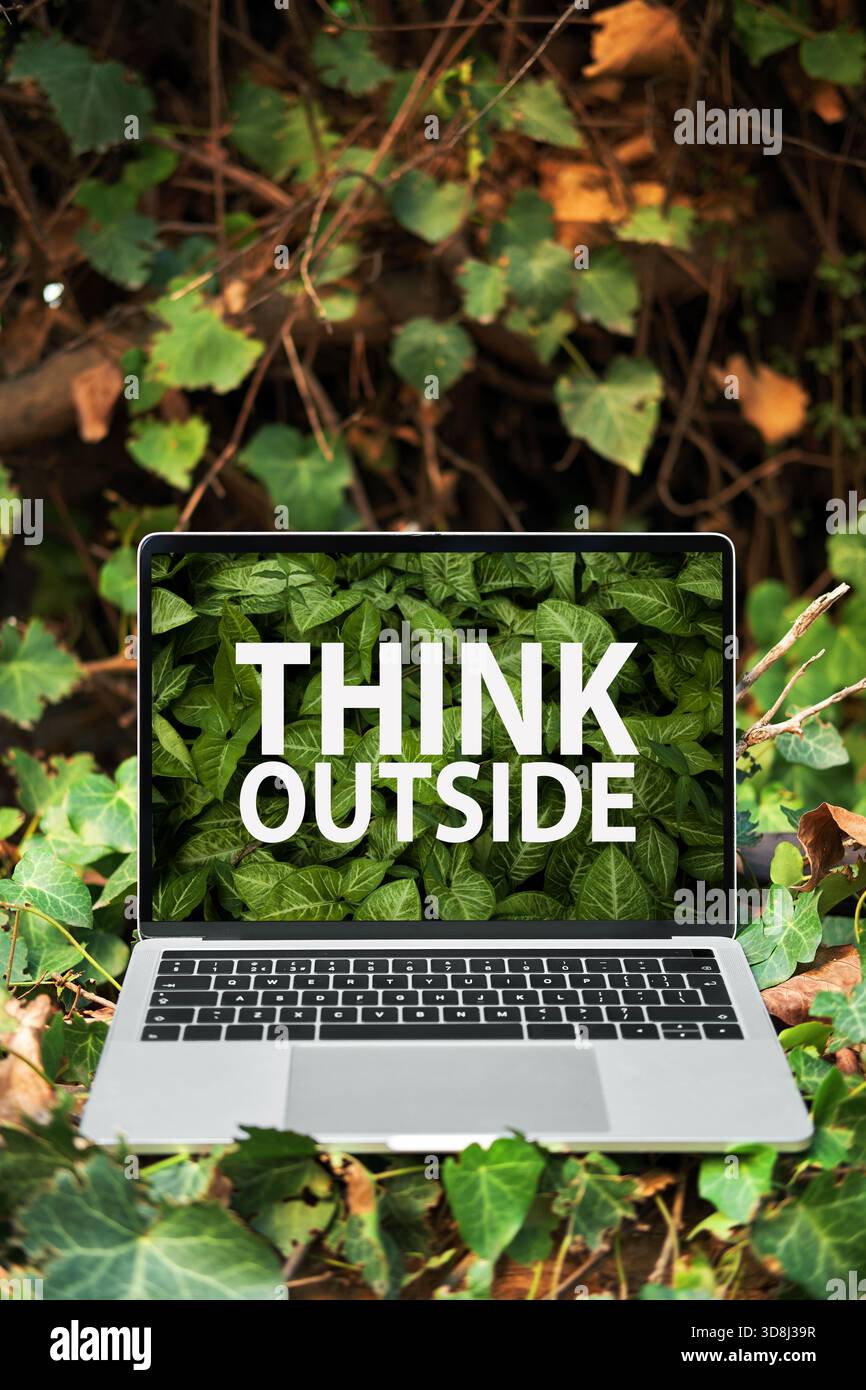 Laptop showing think outside text on its screen, surrounded by lush ...