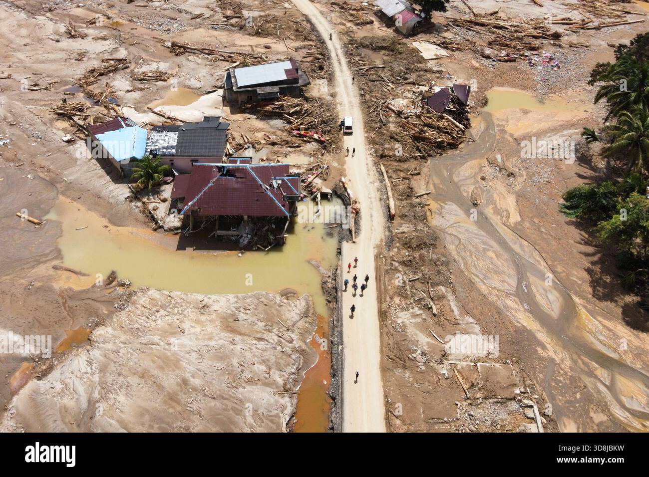 People walk along a road through a village affected by a flash flood in Batang Toru, North ...
