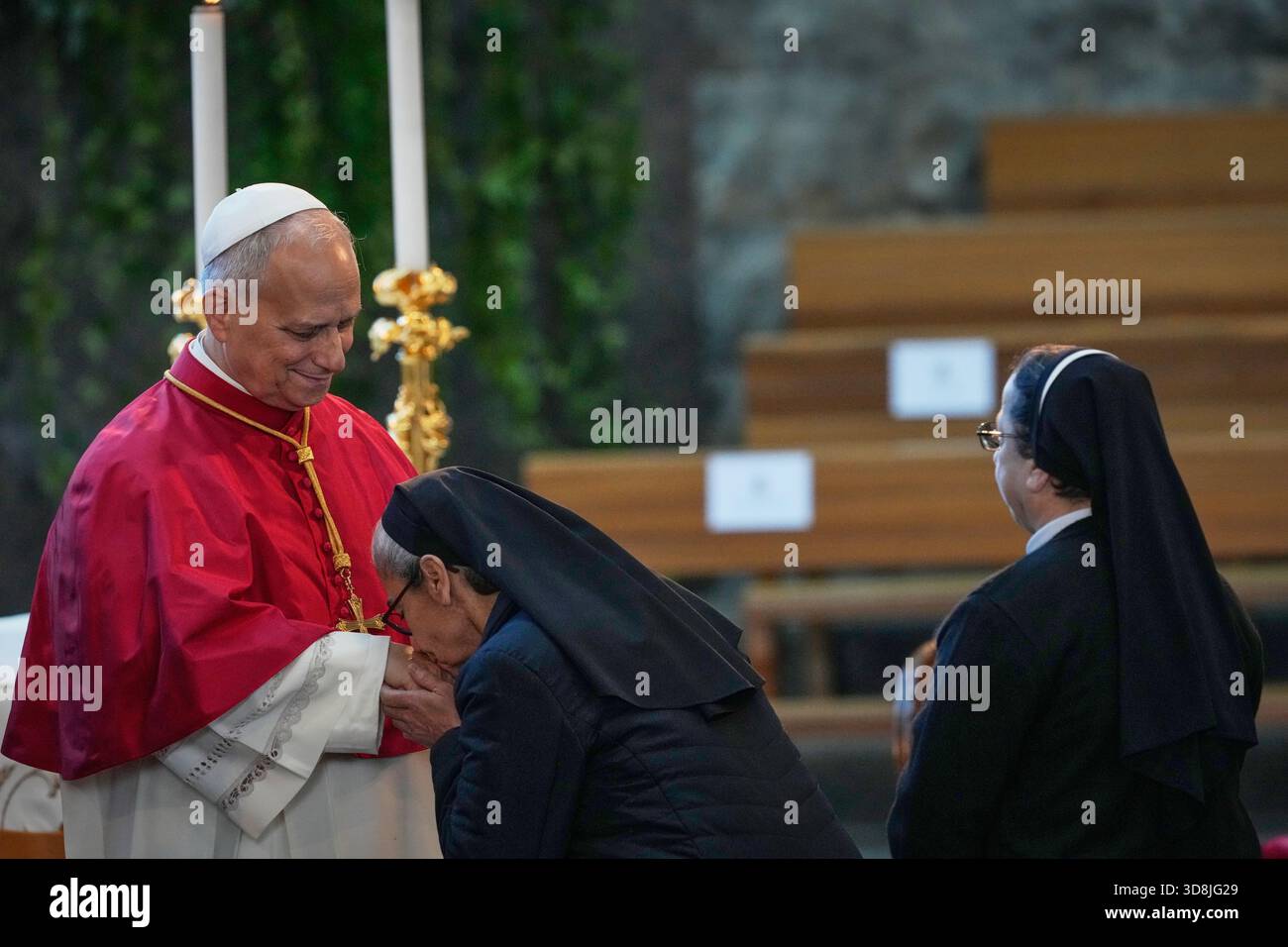 A nun kisses Pope Leo XIV's hand during a gathering with bishops, priests, consecrated persons ...