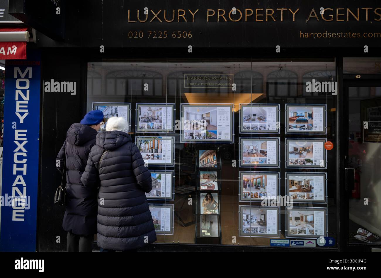 Couple looking at property details advertised in a an estate agents ...