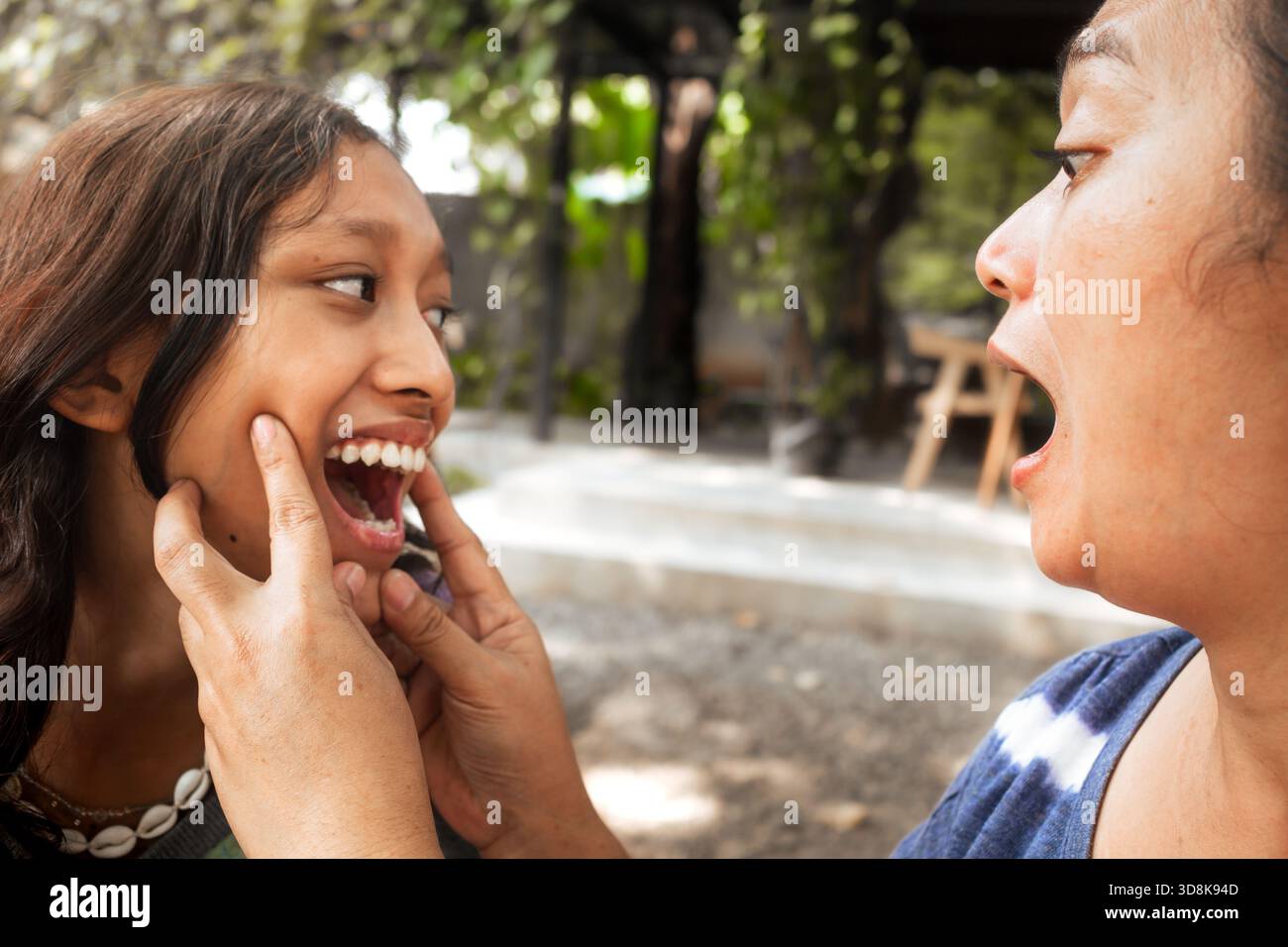 Asian mother asking her teenage daughter to open wide her mouth to ...