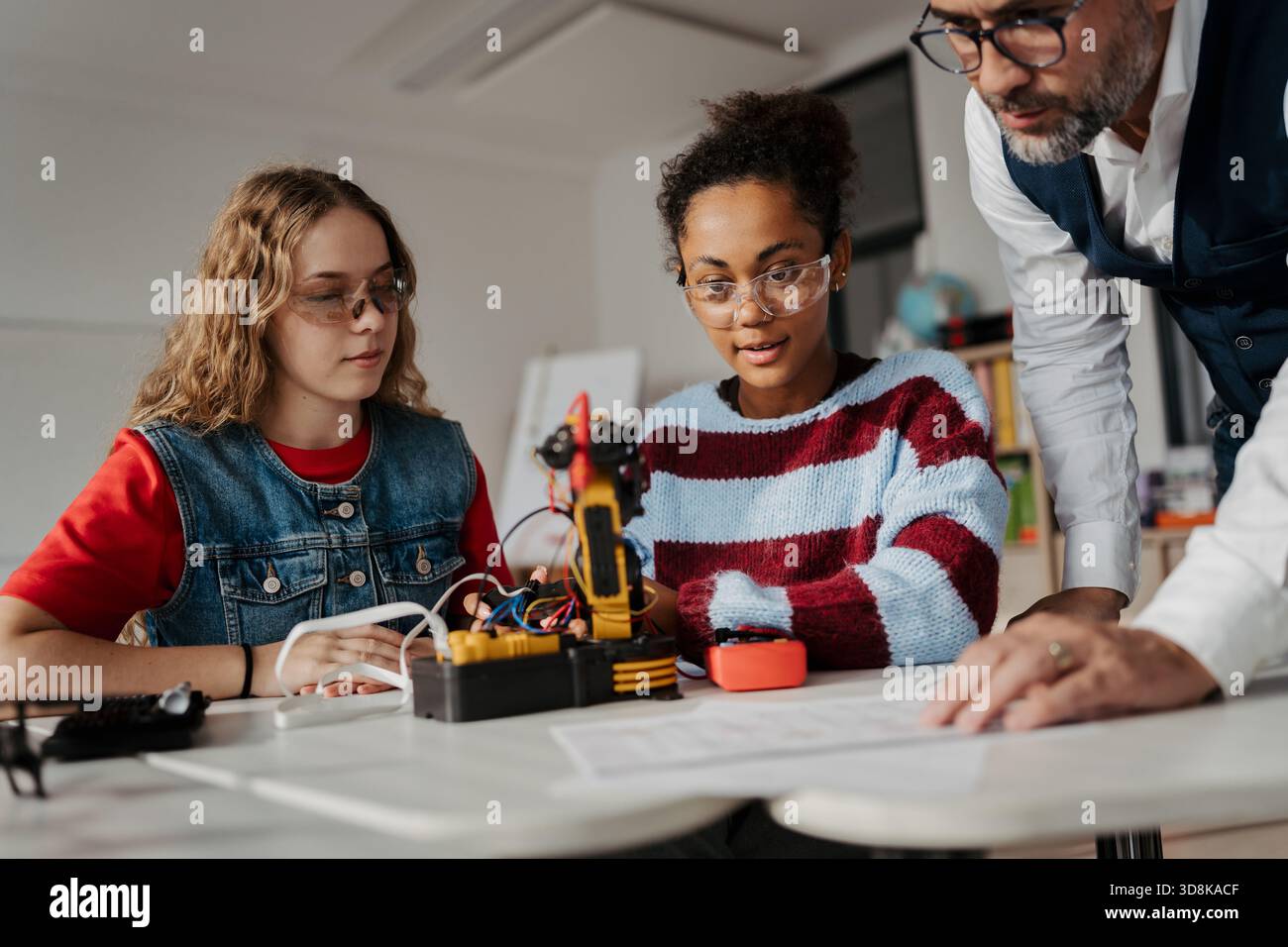 High school students working on robotics project with their teacher ...