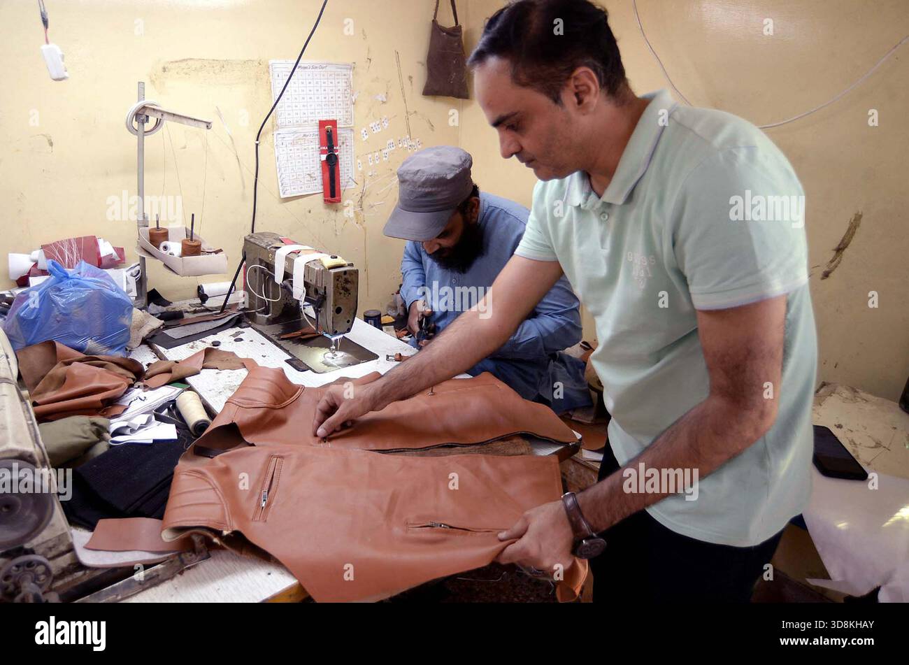 KARACHI, PAKISTAN, DEC 01: Tailor busy in stitching leather warm ...