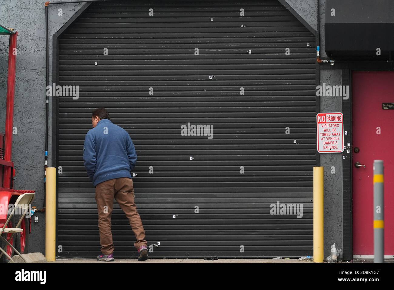 A man looks toward bullet holes where a mass shooting took place ...