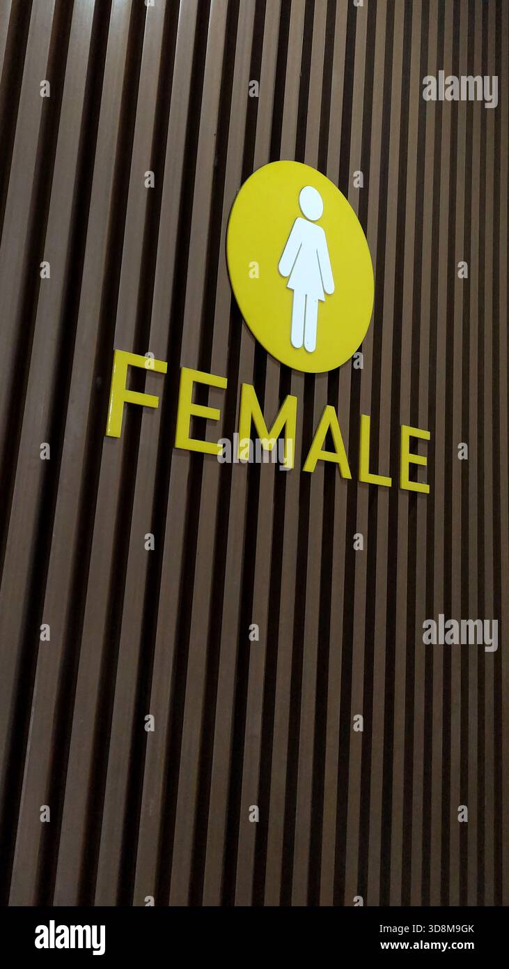 Clear female restroom sign mounted on a modern wooden panel wall ...