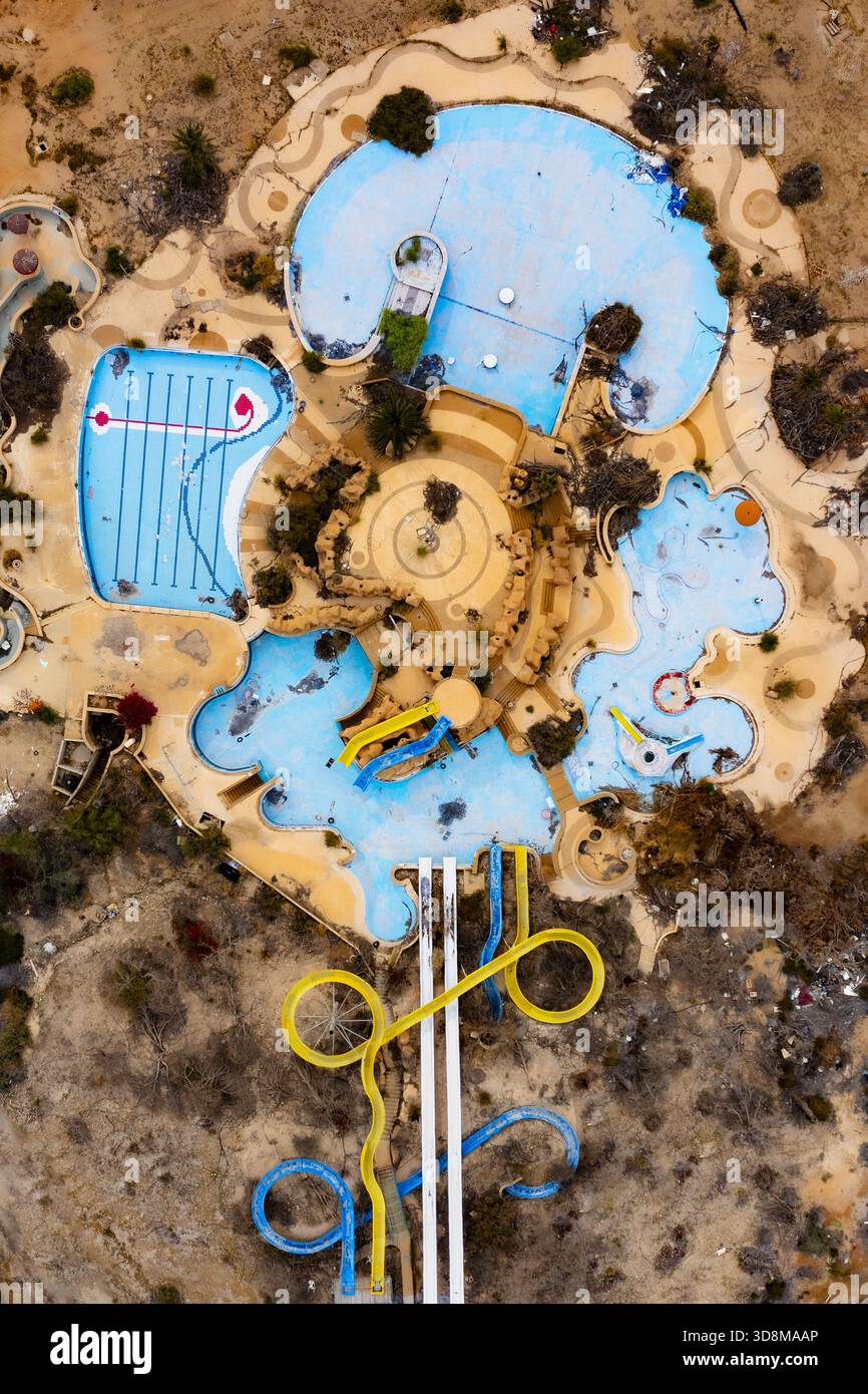 Aerial view of abandoned water park with faded blue pools shaped like ...