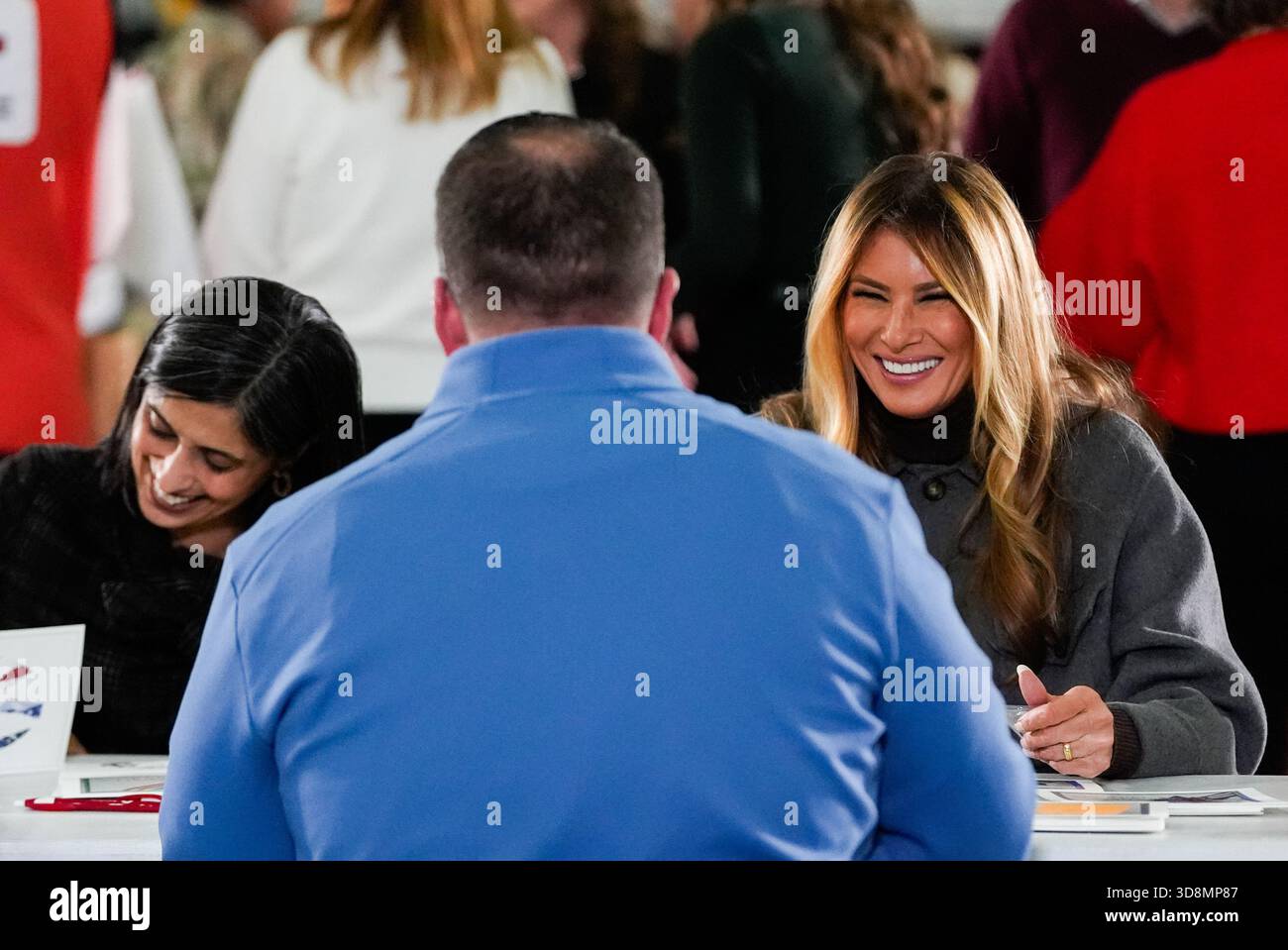 First lady Melania Trump, right, talks to a volunteer while writing ...