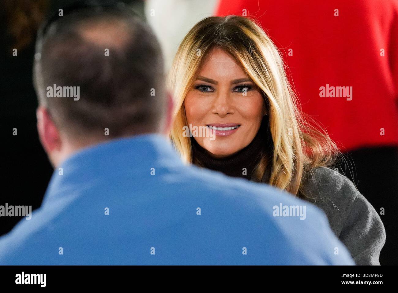 First lady Melania Trump talks to a volunteer while writing holiday ...
