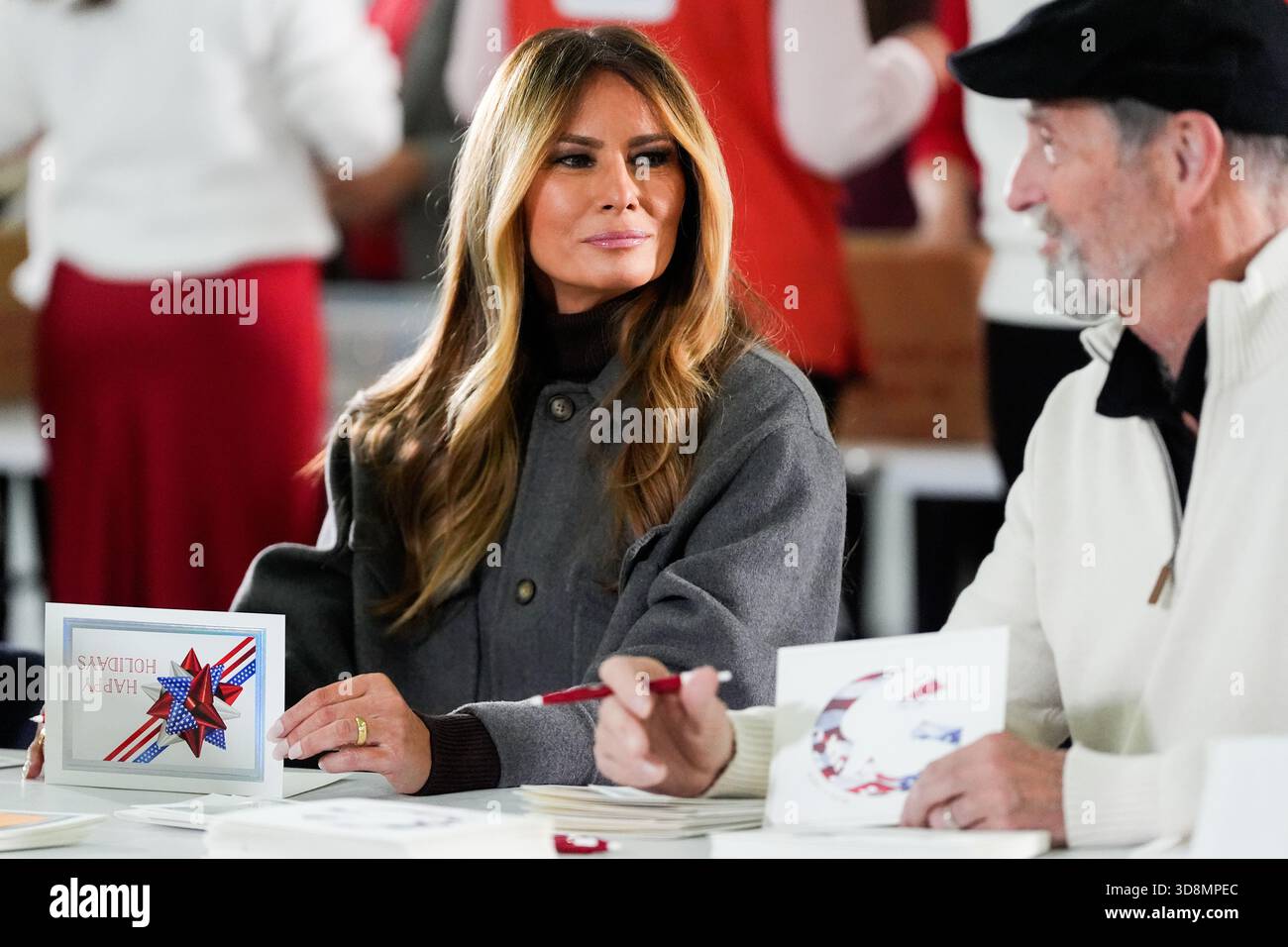 First lady Melania Trump talks to a volunteer while writing holiday ...