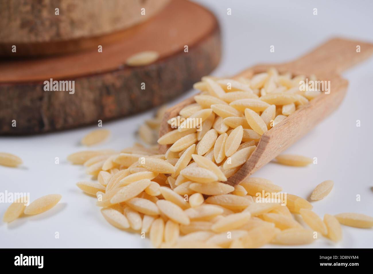 Healthy orzo pasta spilling from wooden scoop Stock Photo - Alamy