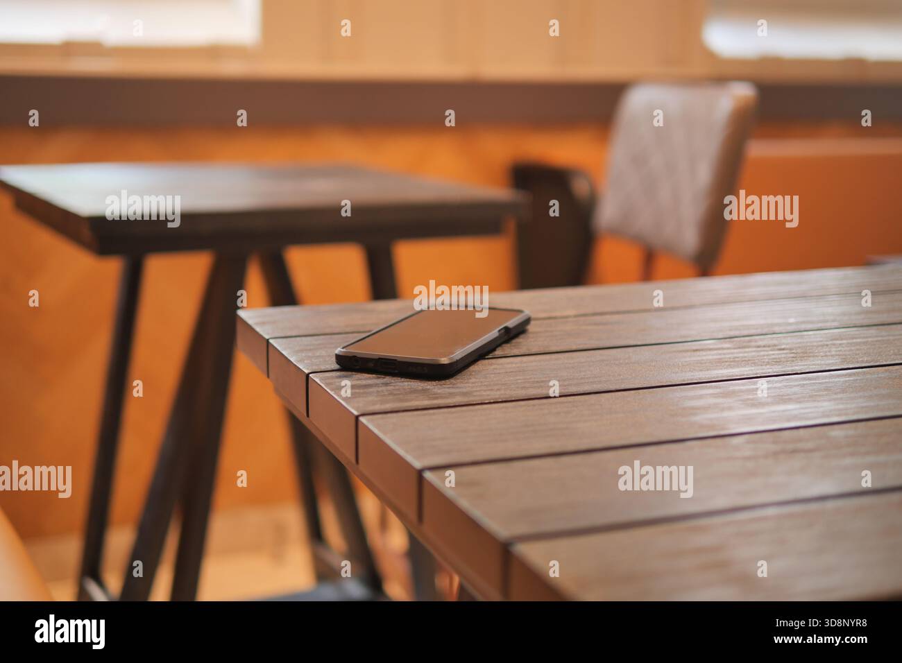 Wooden table with a smartphone placed on it in a cafe. lost smart phone ...