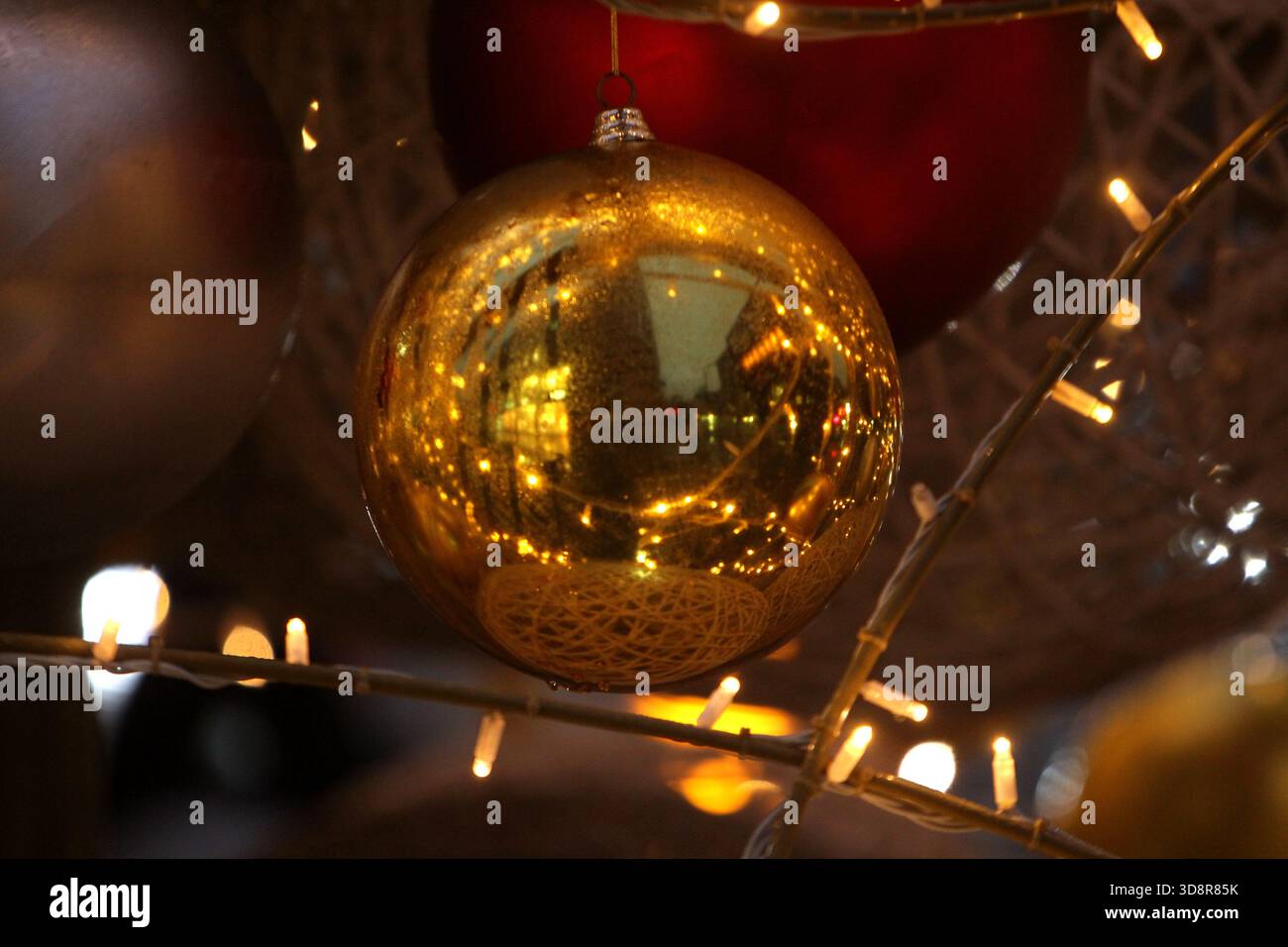 String lights reflect in a golden bauble on a Christmas tree on ...
