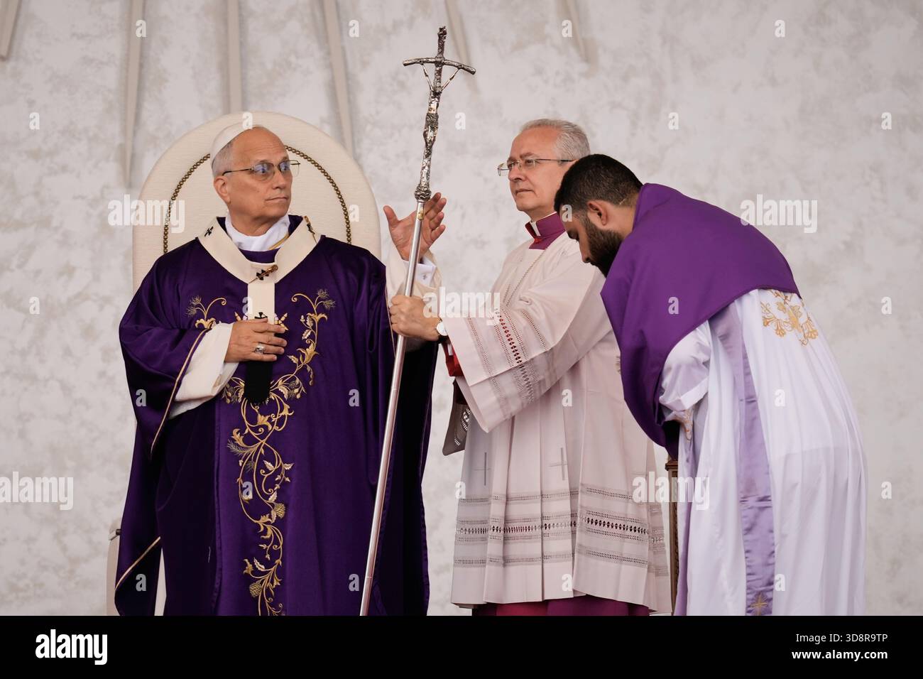 A priest hands the papal ferula to Pope Leo XIV as he celebrates Holy ...