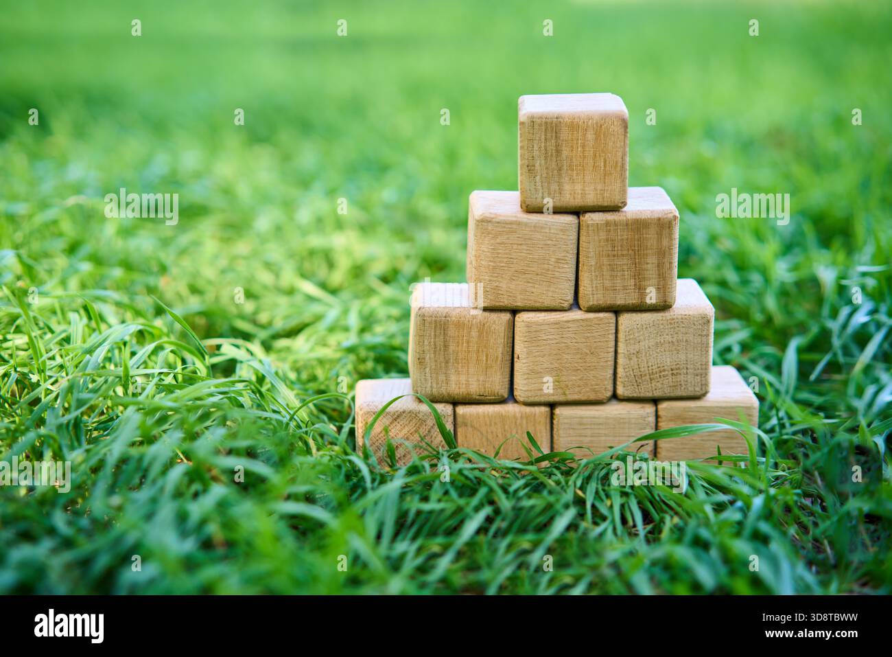 Pyramid of blank wooden cubes with copy space on fresh green grass in ...
