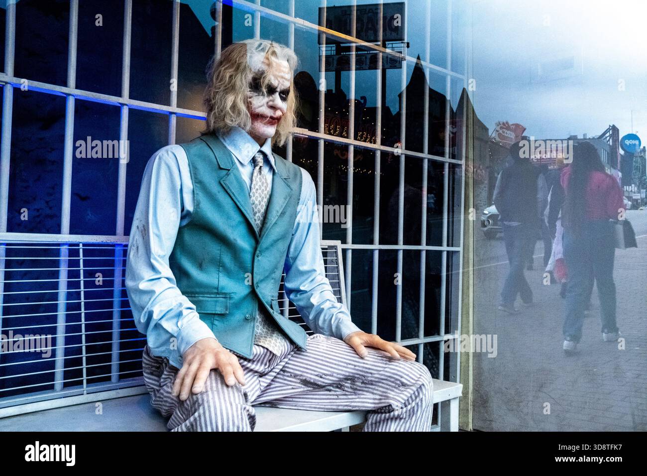 A life size figure resembling a clown villain sits inside a storefront ...