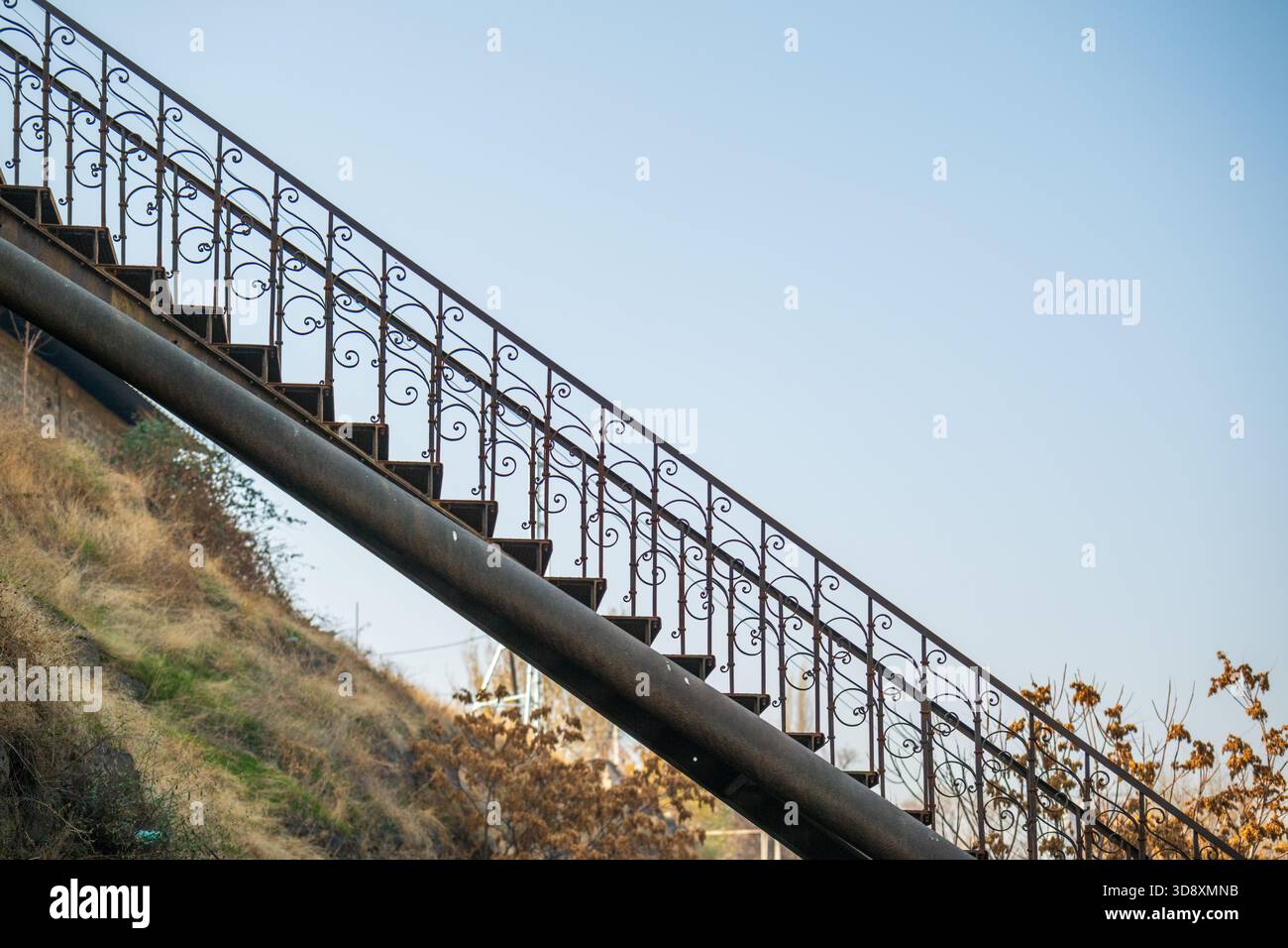 A set of iron stairs with a metal rail. The stairs are on a hill and ...