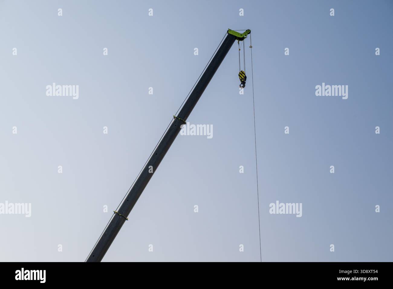 A crane is lifting a person up high in the air. The crane is tall and ...