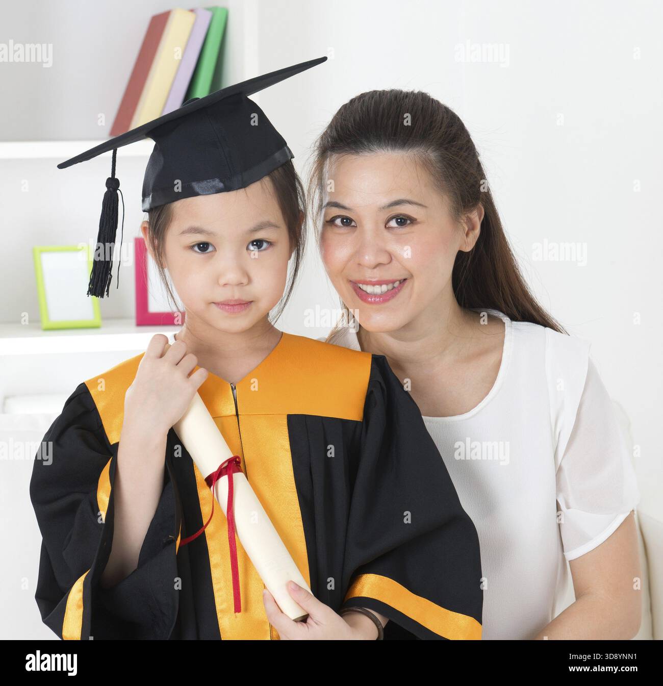 Asian school kid graduate in graduation gown and cap. Taking photo with ...
