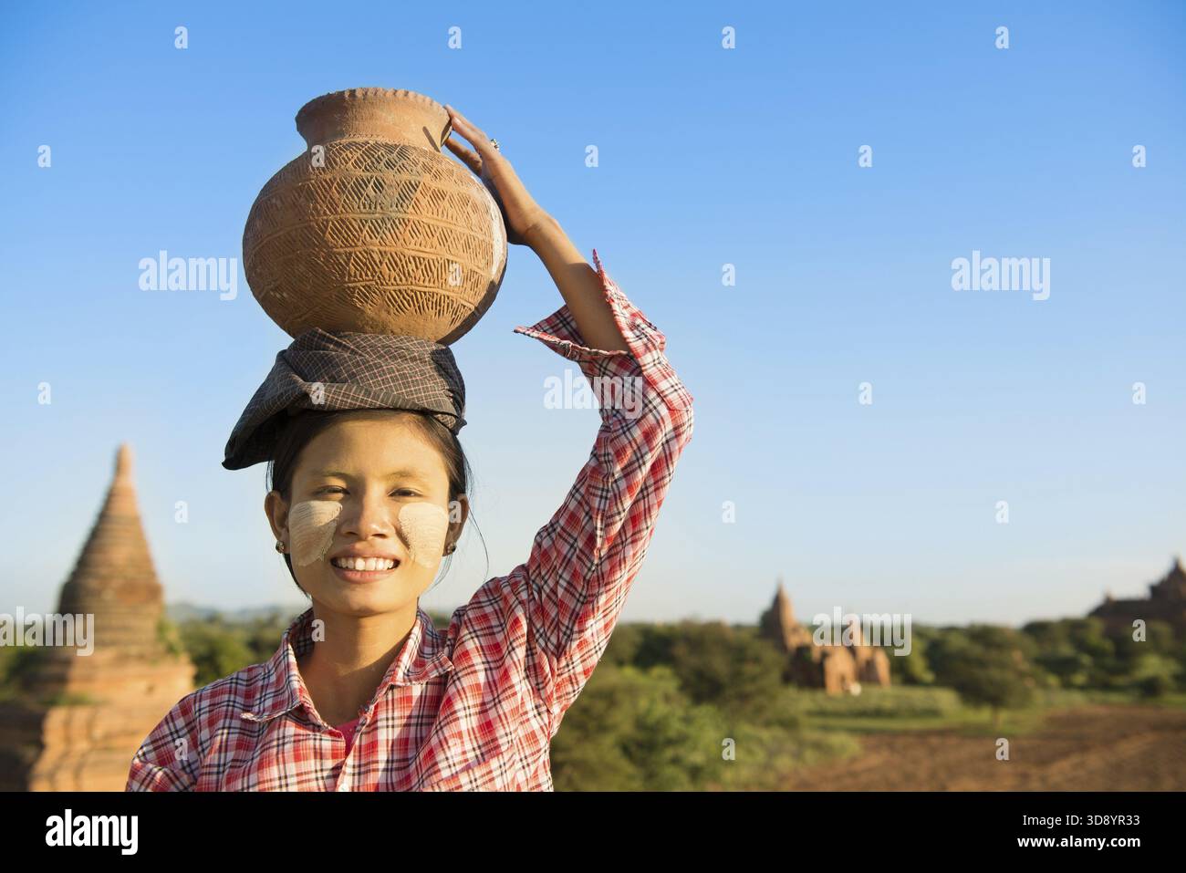 Portrait of Young Asian Burmese traditional female farmer carrying clay ...