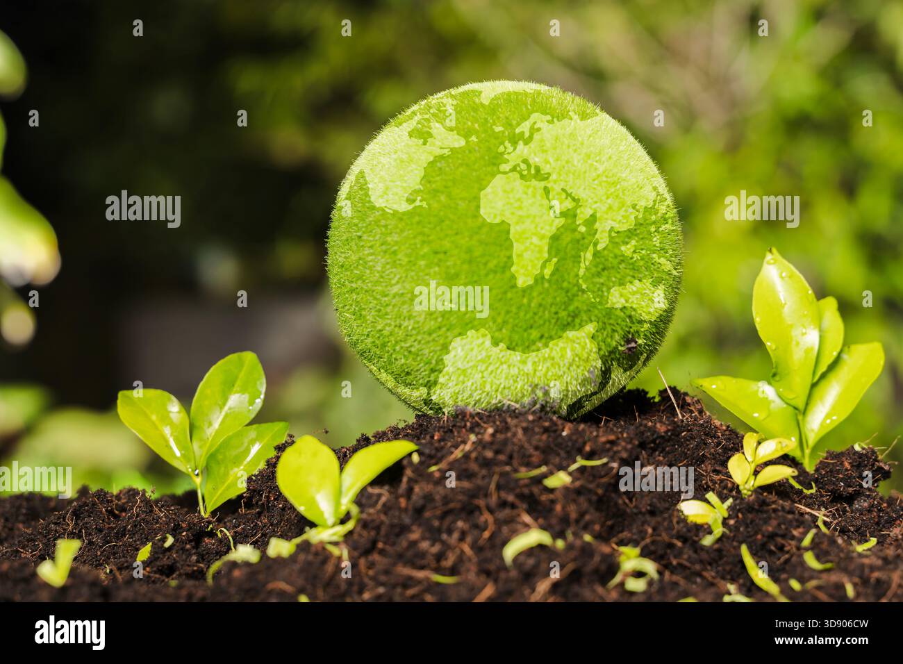 A green earth globe resting on soil with young seedlings symbolizes ...