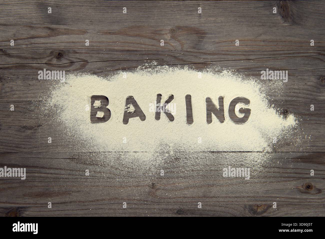 Word baking written in white flour on a old wooden table, low light ...