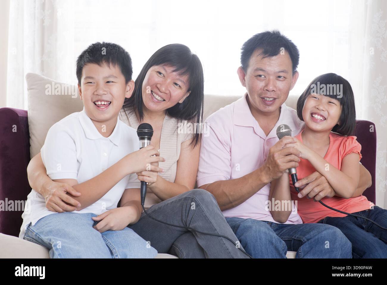 Family at home. Portrait of a happy Asian family singing karaoke ...