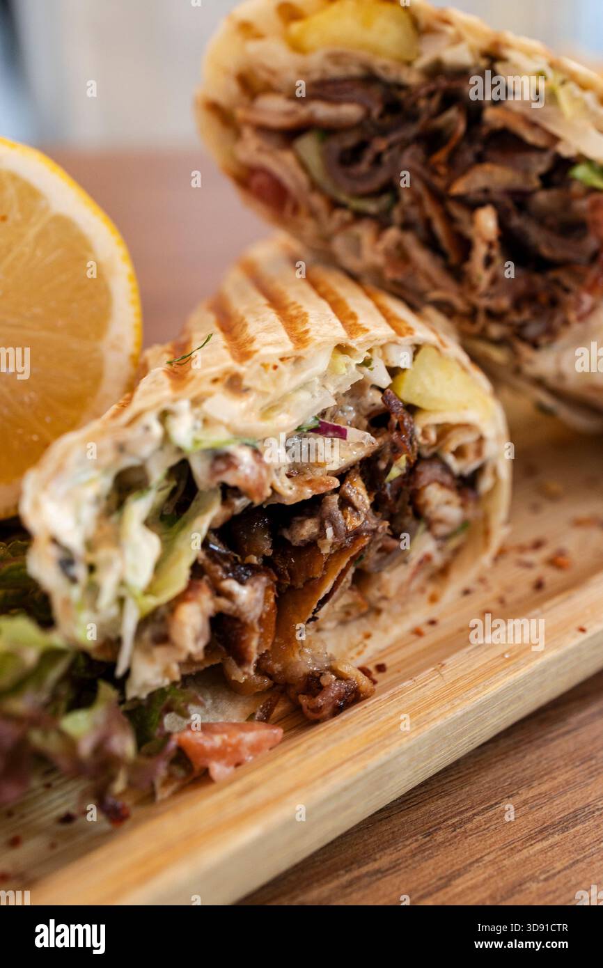 Doner kebab wrap, filled with meat and vegetables, cut in half with ...