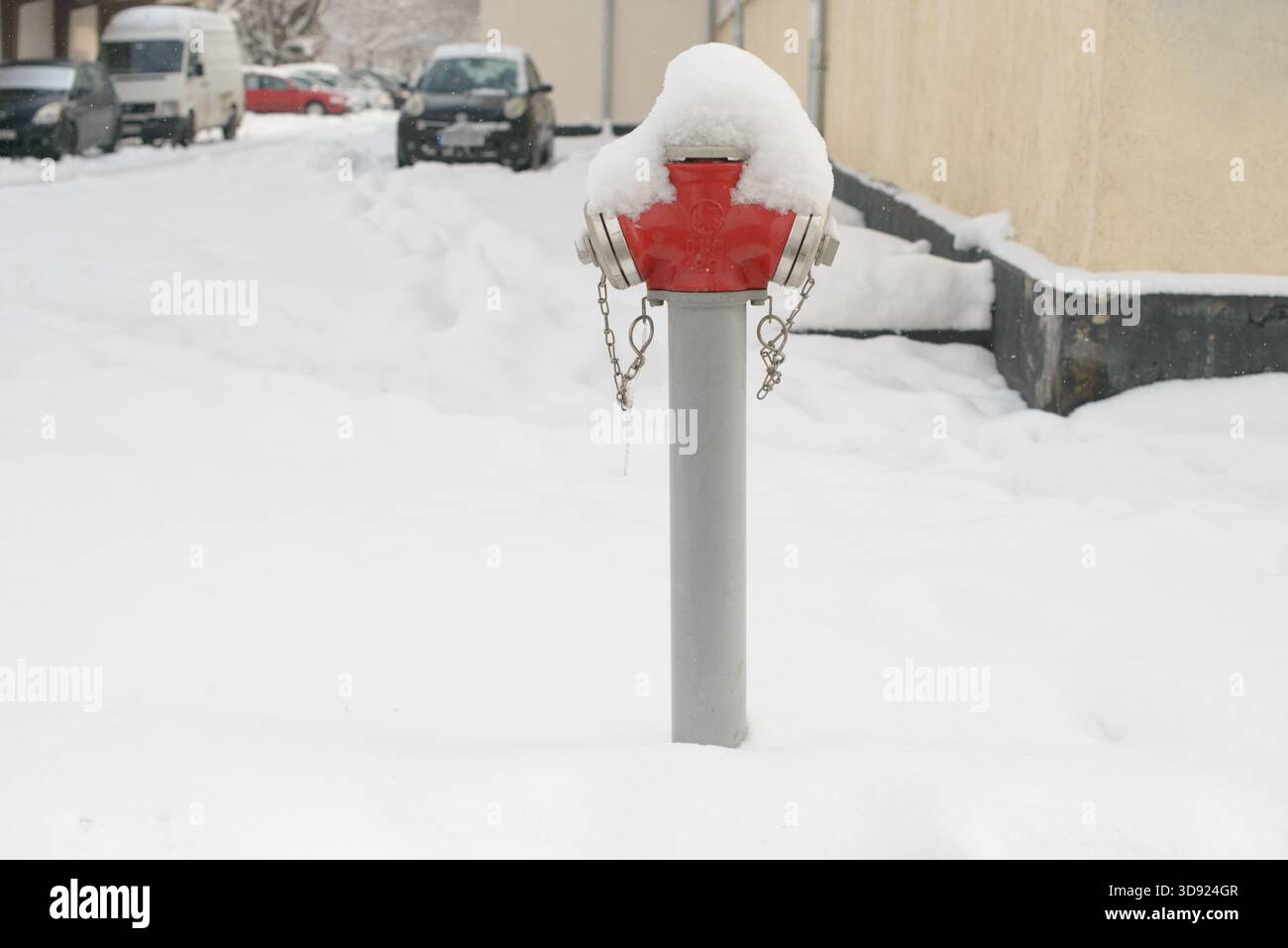 A red fire hydrant rises from deep snow in a quiet winter street, its ...