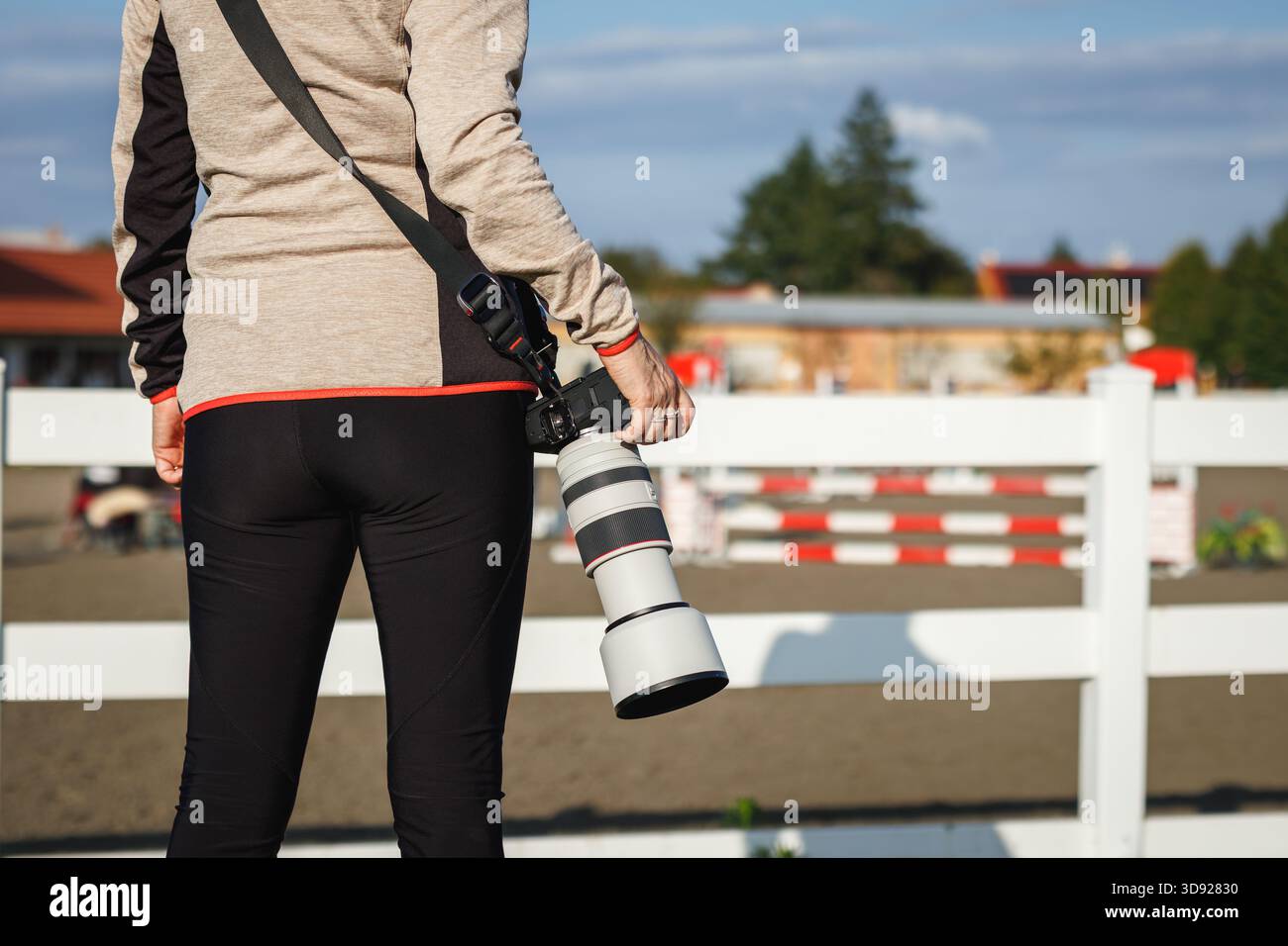 Sport photographer holding camera with telephoto lens at equestrian ...