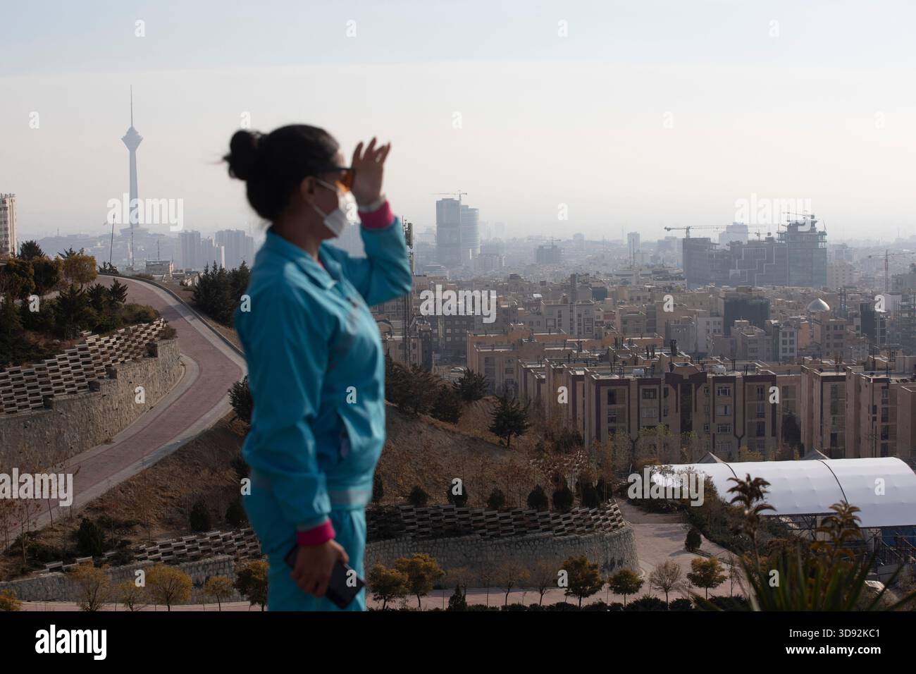 03 December 2025, Iran, Teheran: A woman looks out over the smog-ridden ...