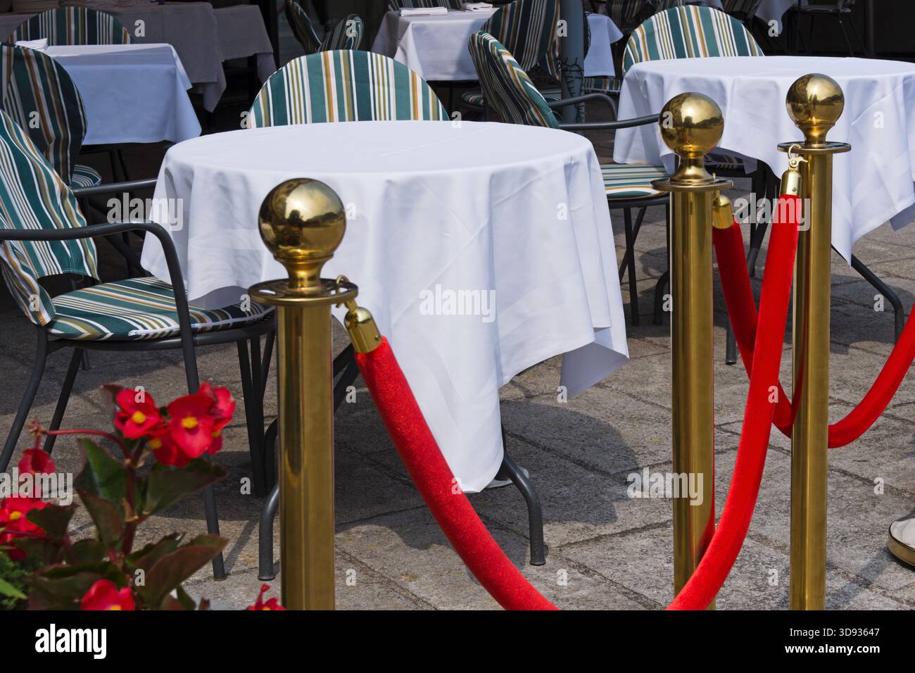 outdoor restaurant tables and red velvet rope barrier Stock Photo - Alamy