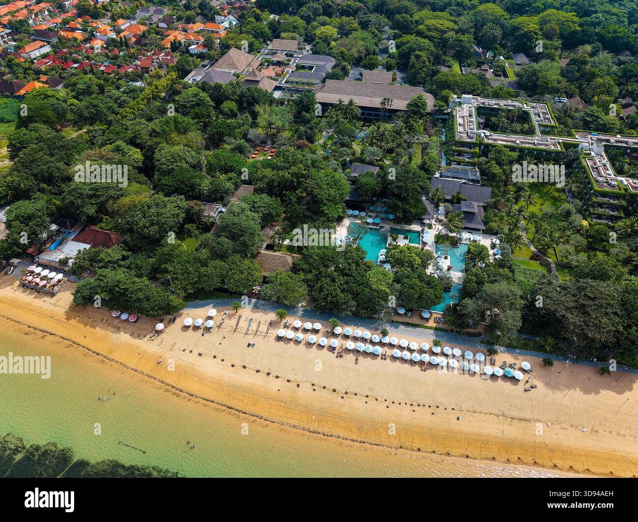 Lush tropical trees surrounding a luxury resort on the golden sands of ...