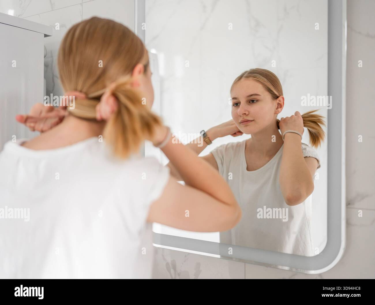Teen Girl Tying Hair In A Ponytail At Home In The Bathroom Stock Photo ...