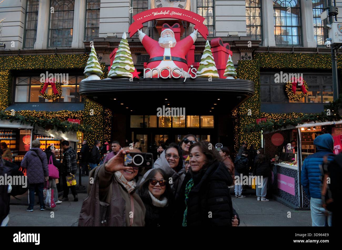 People take photos in front of a Macy’s department store, which is decorated in Christmas ...