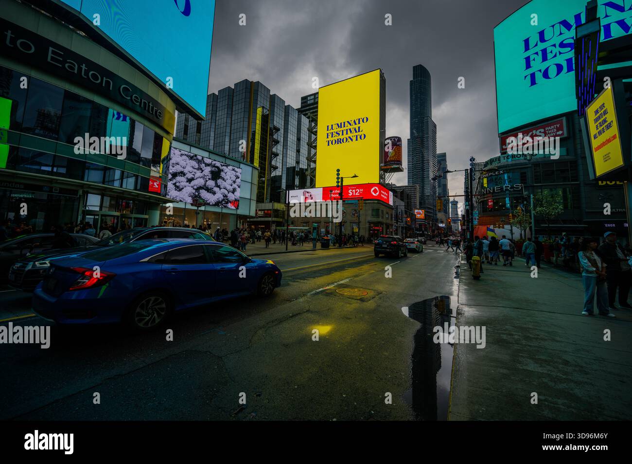 Traffic and pedestrians move along a wet downtown street lined with ...