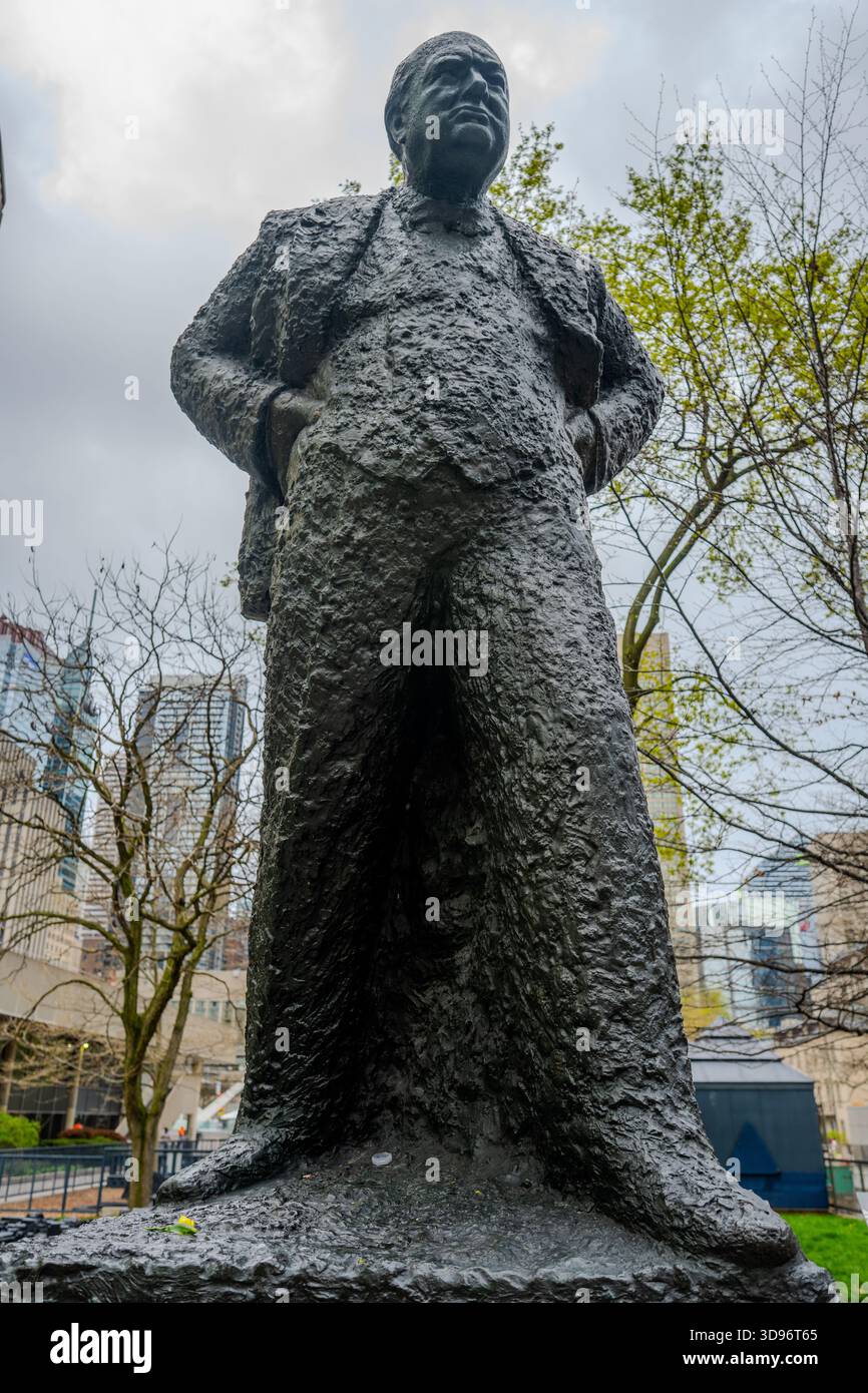 Large bronze statue of a man in a suit stands in a city park in ...