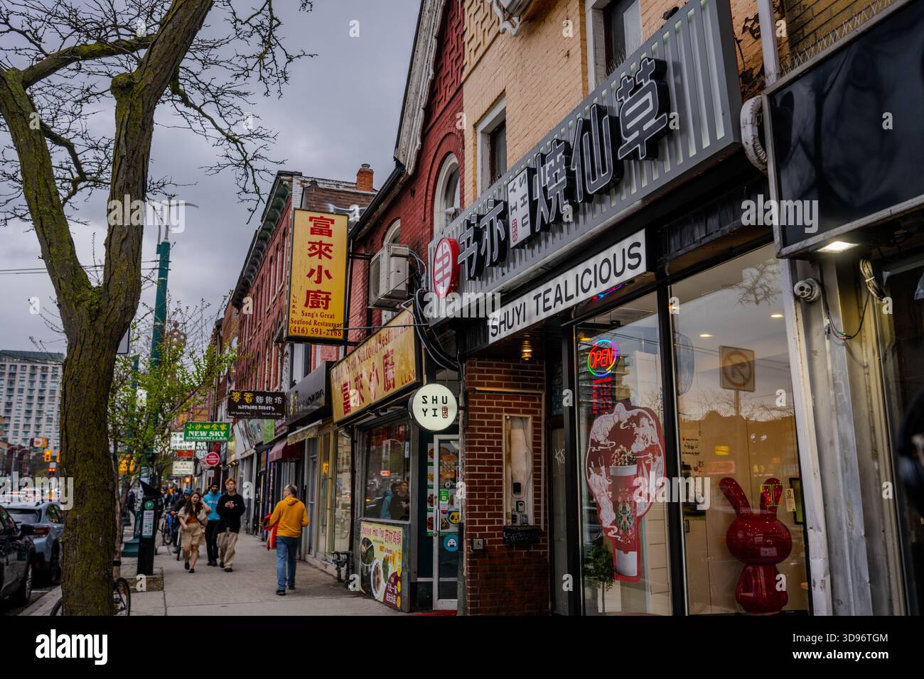 Pedestrians walk past restaurants and shops with Chinese signage on a ...