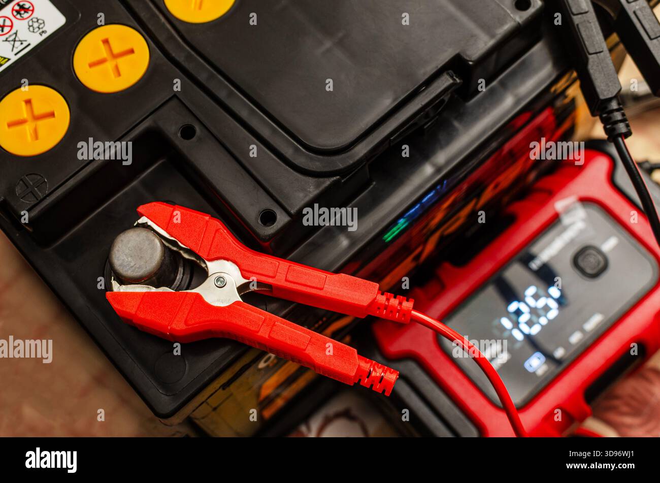 close-up view of a car battery connected to a portable charger, showing ...