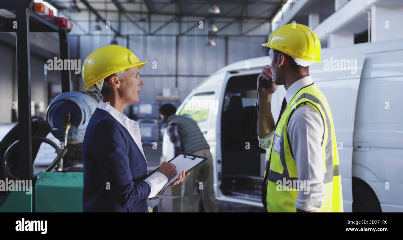 Talking supervisor in suit and foreman in hi-vis vest loading cargo in ...