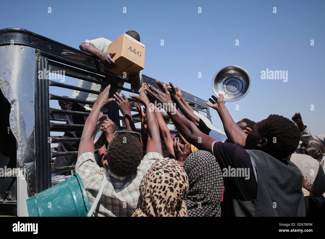 FILE.- Sudanese families displaced from El-Fasher reach out as aid workers distribute food ...
