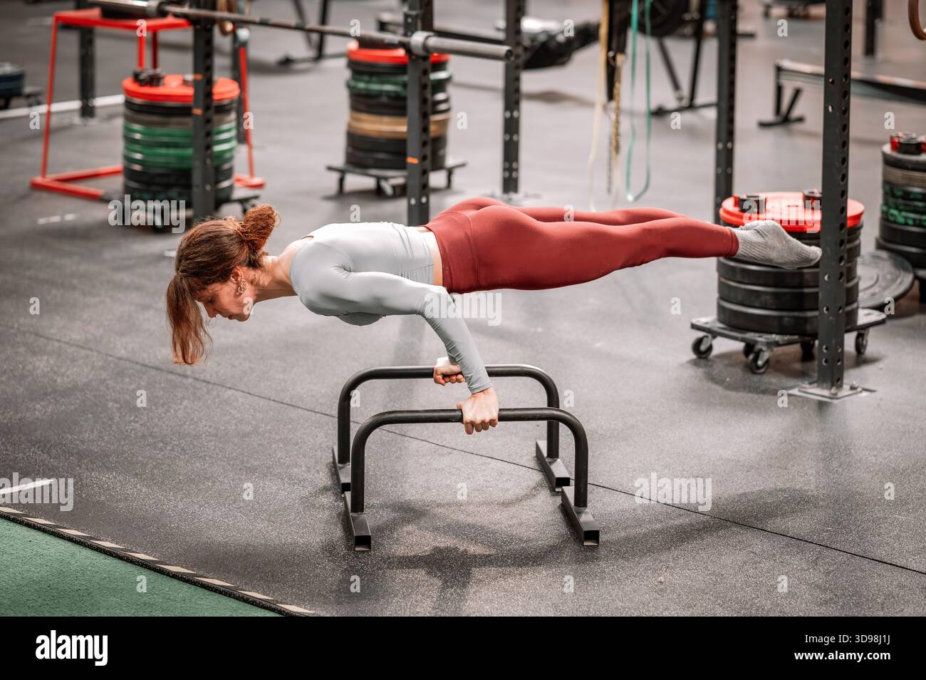 Woman balancing her body on parallettes, demonstrating strength ...